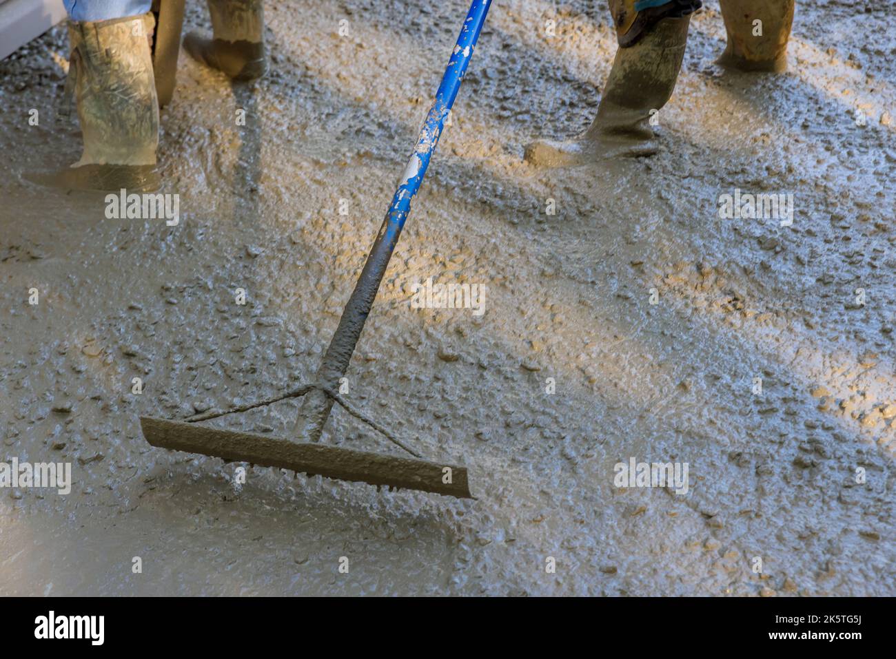 Pour wet concrete while paving driveway at construction site near new ...
