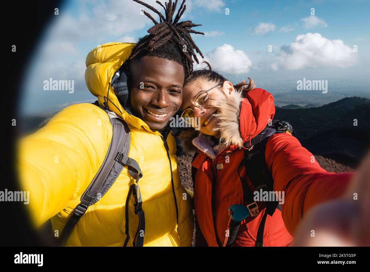 Diverse multiethnic couple of young hikers taking selfie on the peak of ...