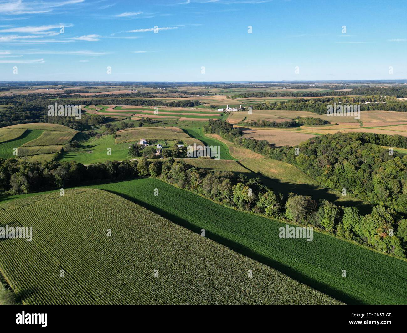 An aerial shot of a countryside with wide green agricultural fields and ...