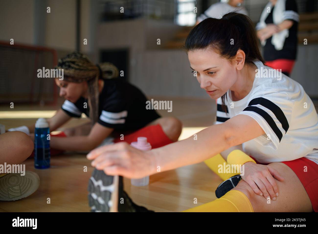 Happy women stretching before basketball match in gym Stock Photo - Alamy