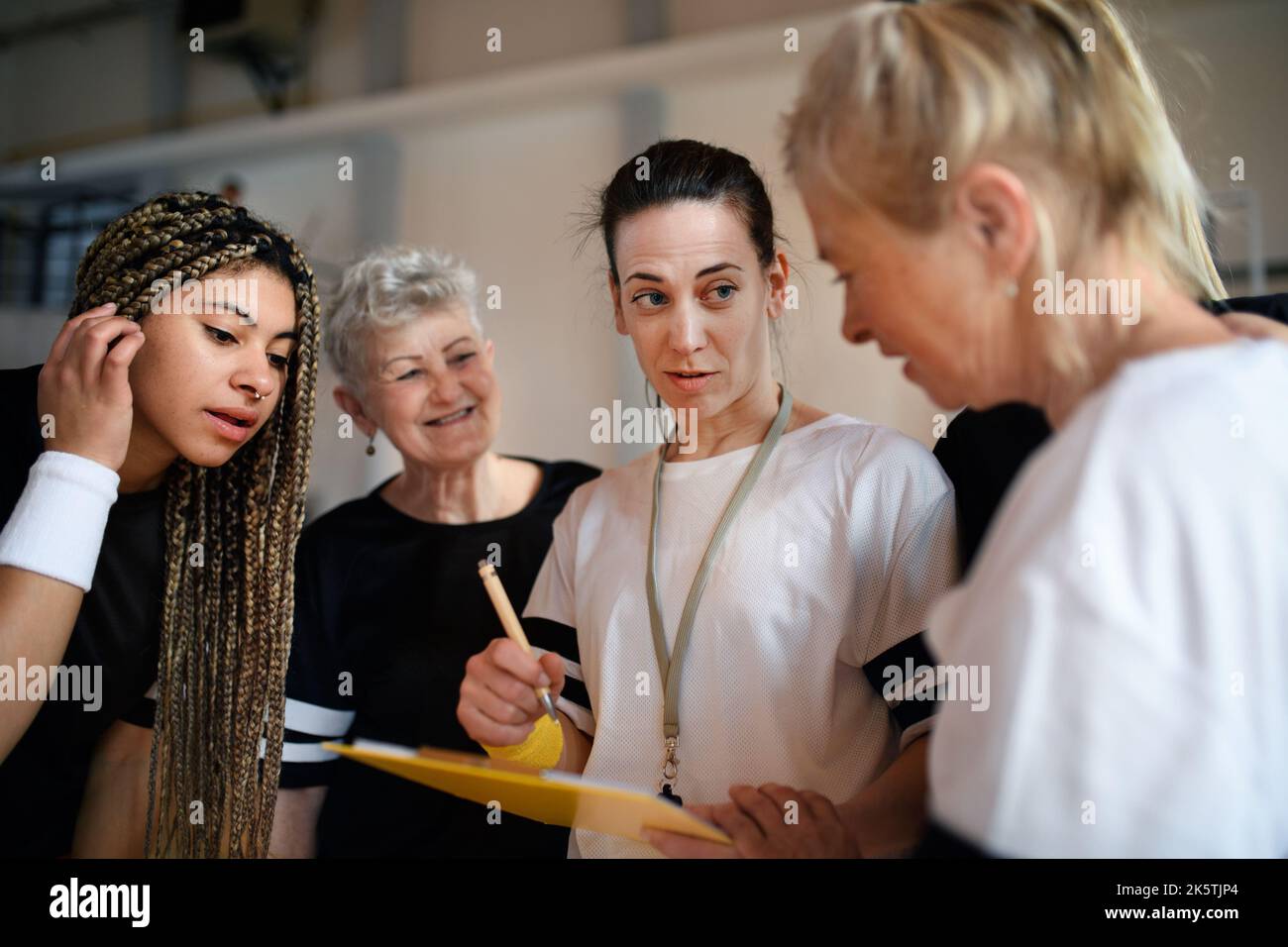 Female sport coach with clipboard discussing tactics with young and old ...