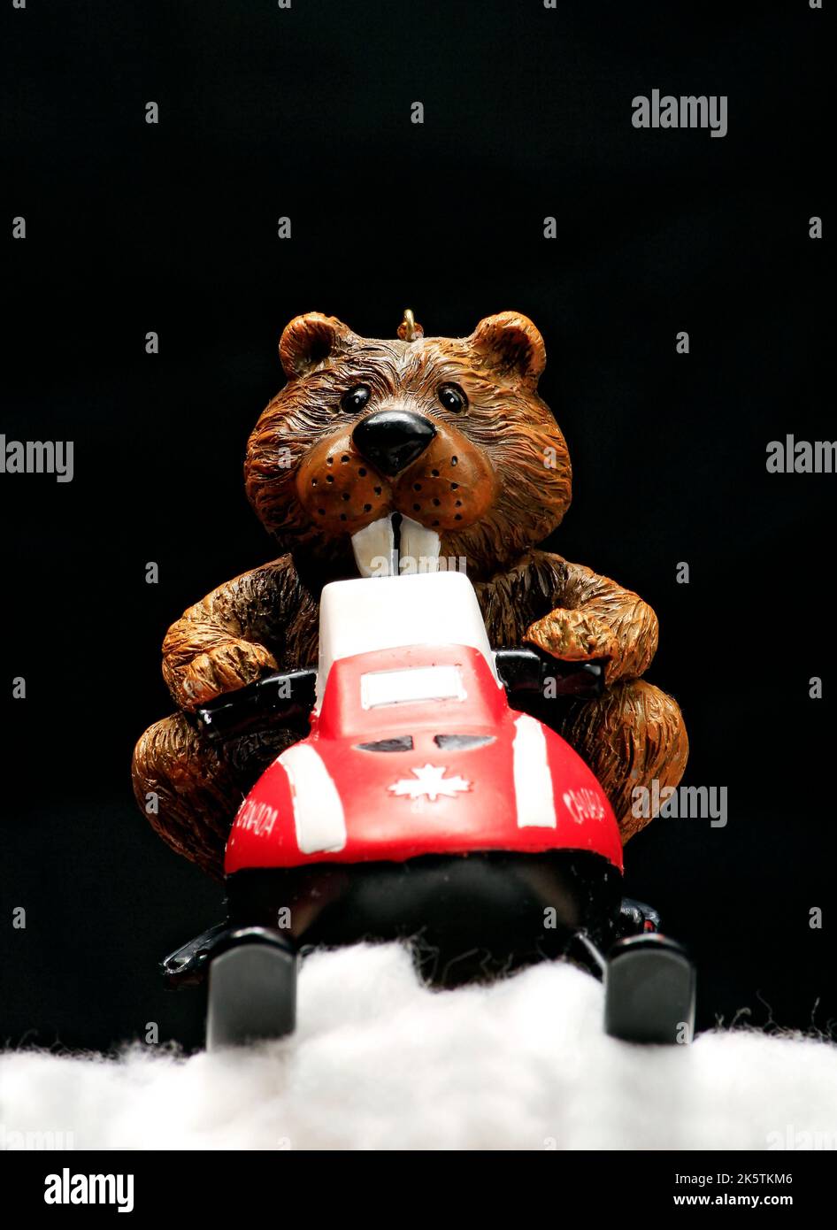 A vertical shot of a Christmas ornament depicting a beaver riding a ...