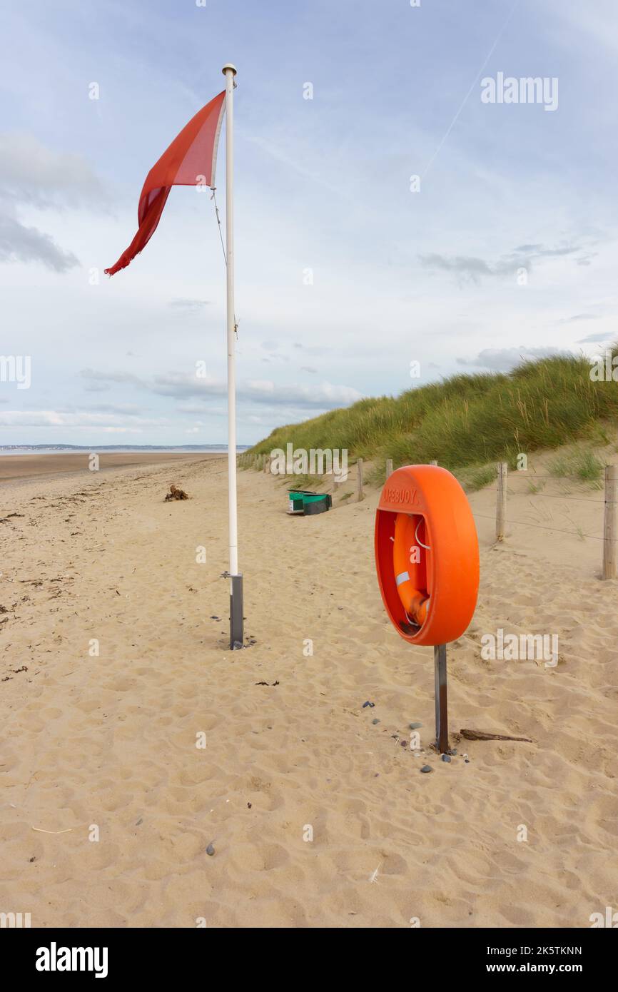 Red warning flag with a life buoy on a beach advising bathers it is ...