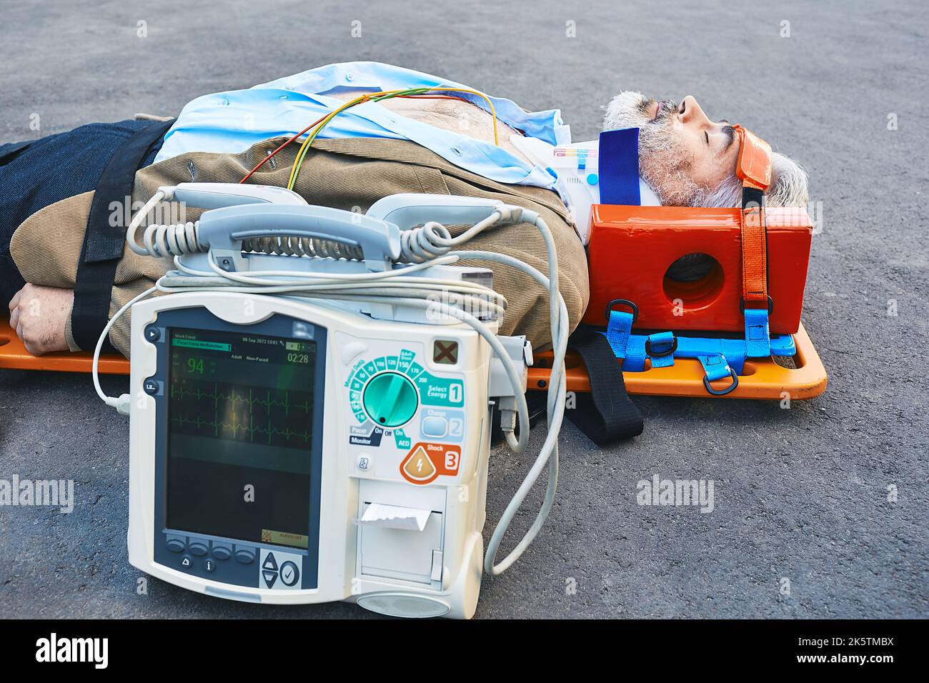 Electrocardiogram equipment outside ambulance near laying male victim ...