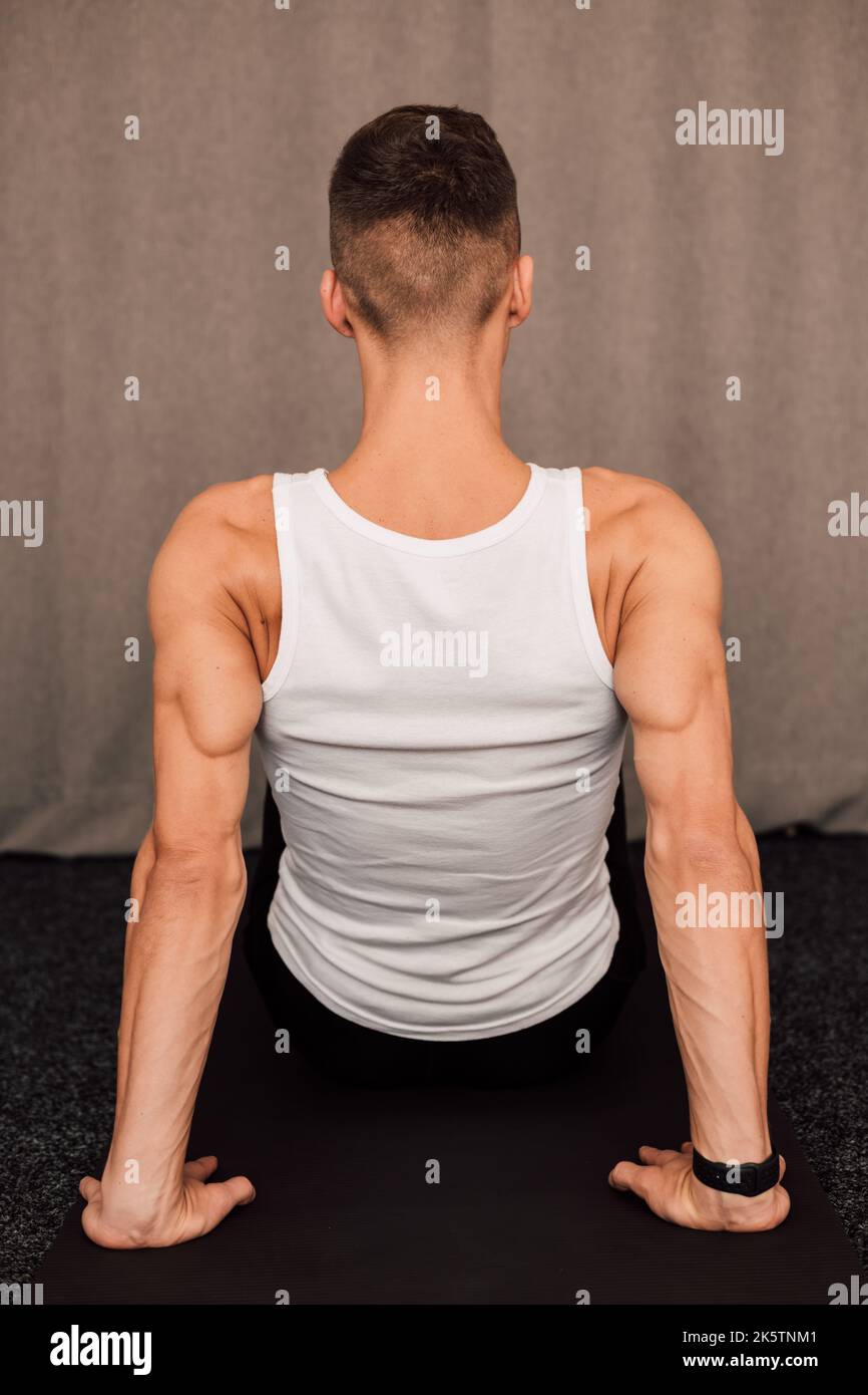 A young handsome athlete stands in a bar indoors. Rear view Stock Photo ...