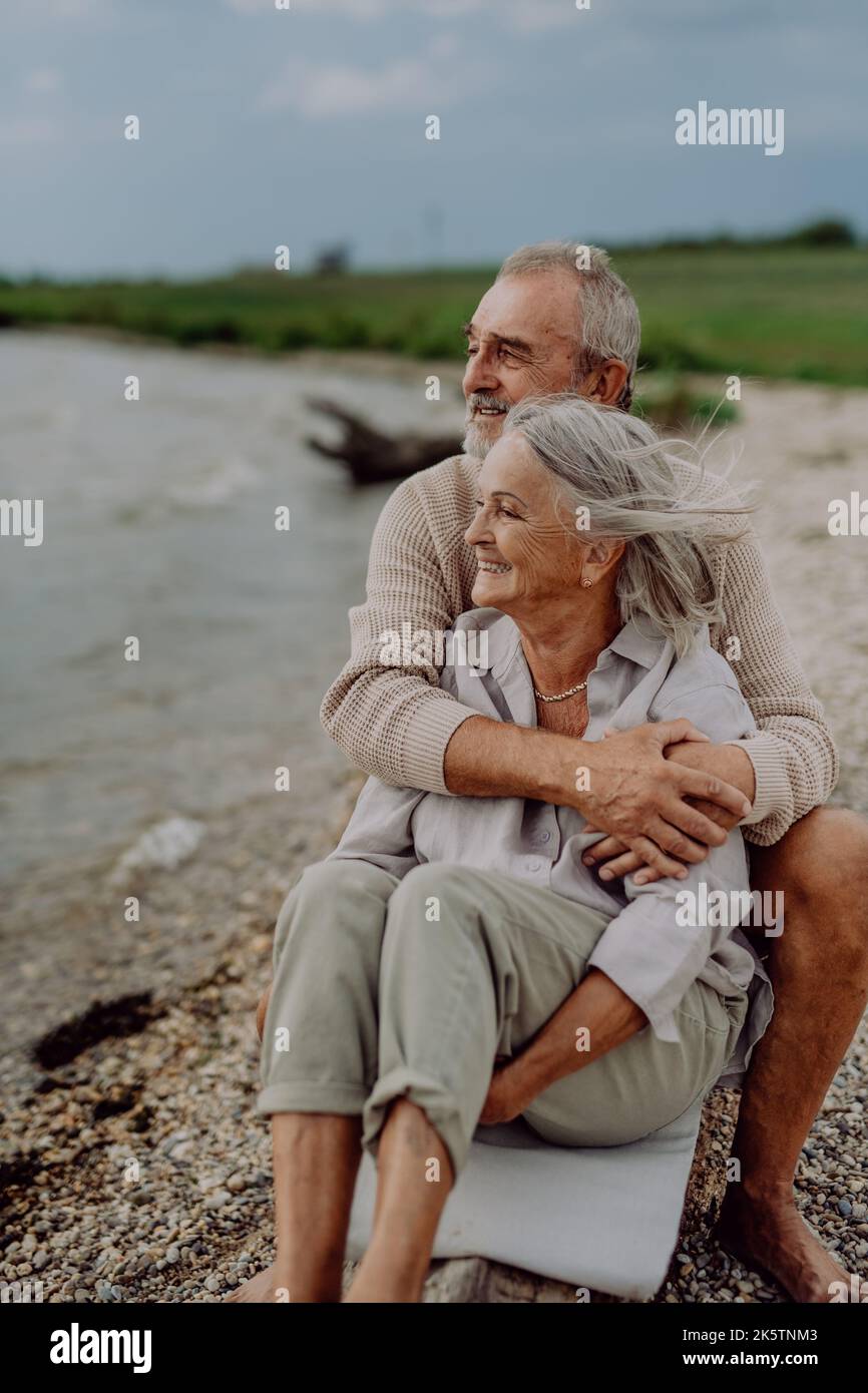 Senior couple sitting and having romantic moment near the autumn sea ...