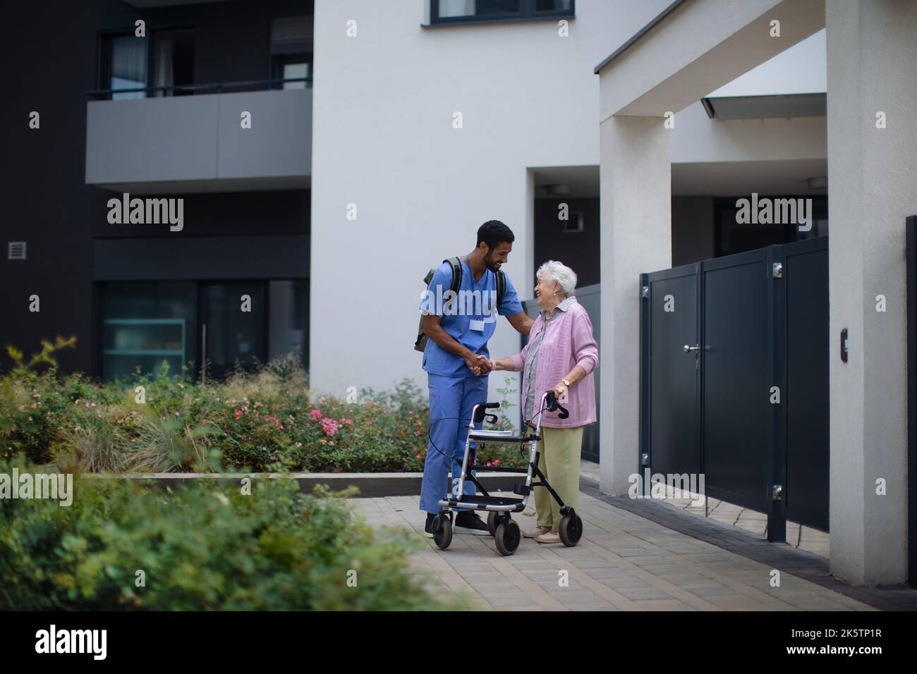 Caregiver walking with senior woman client in front of nurishing home ...