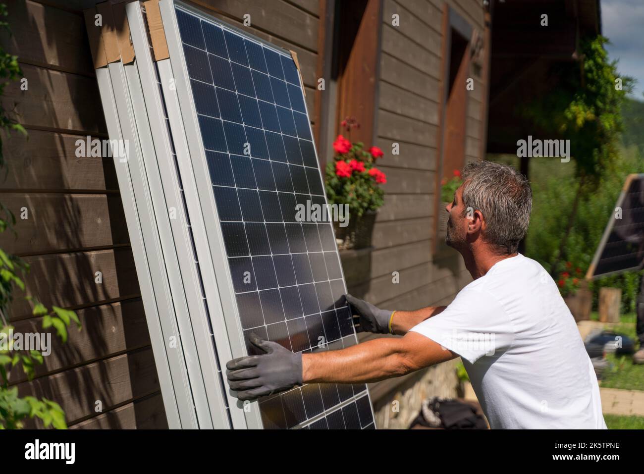 Mature man worker carrying solar panel for installing Stock Photo - Alamy