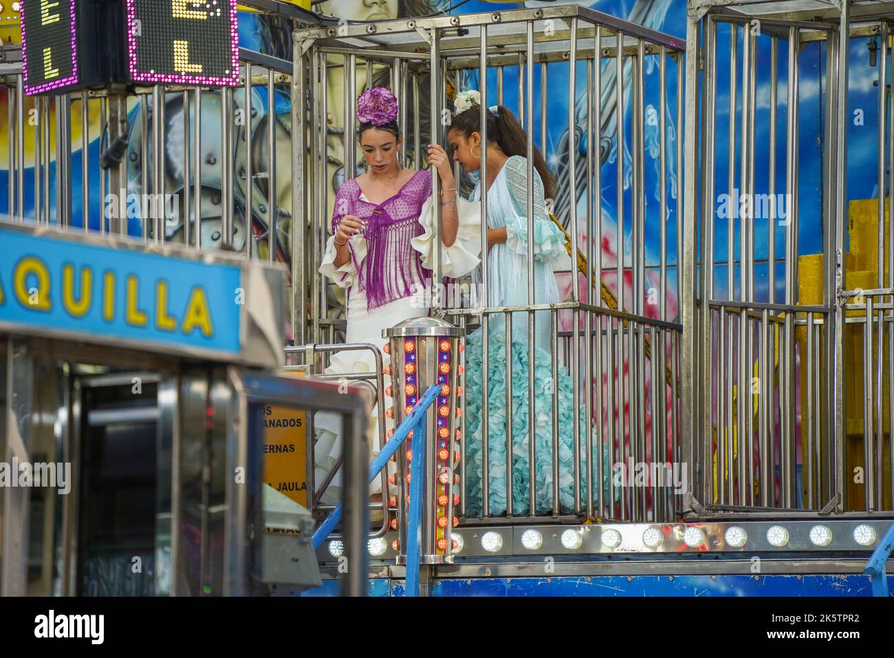 Two girls dressed in flamenco style at annual fair amusement ride on ...