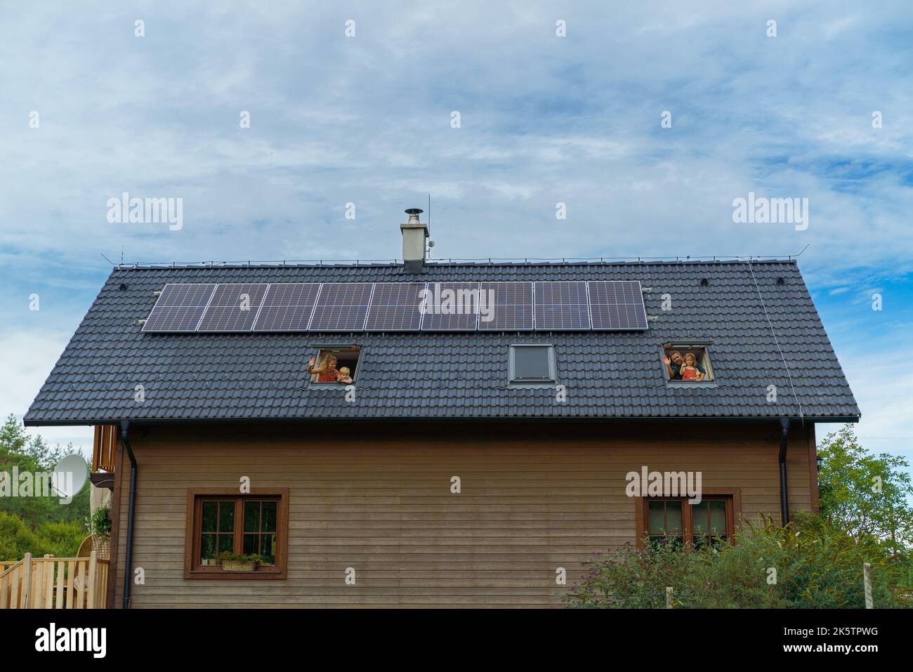 Happy family waving from skylight windows in their new house with solar ...
