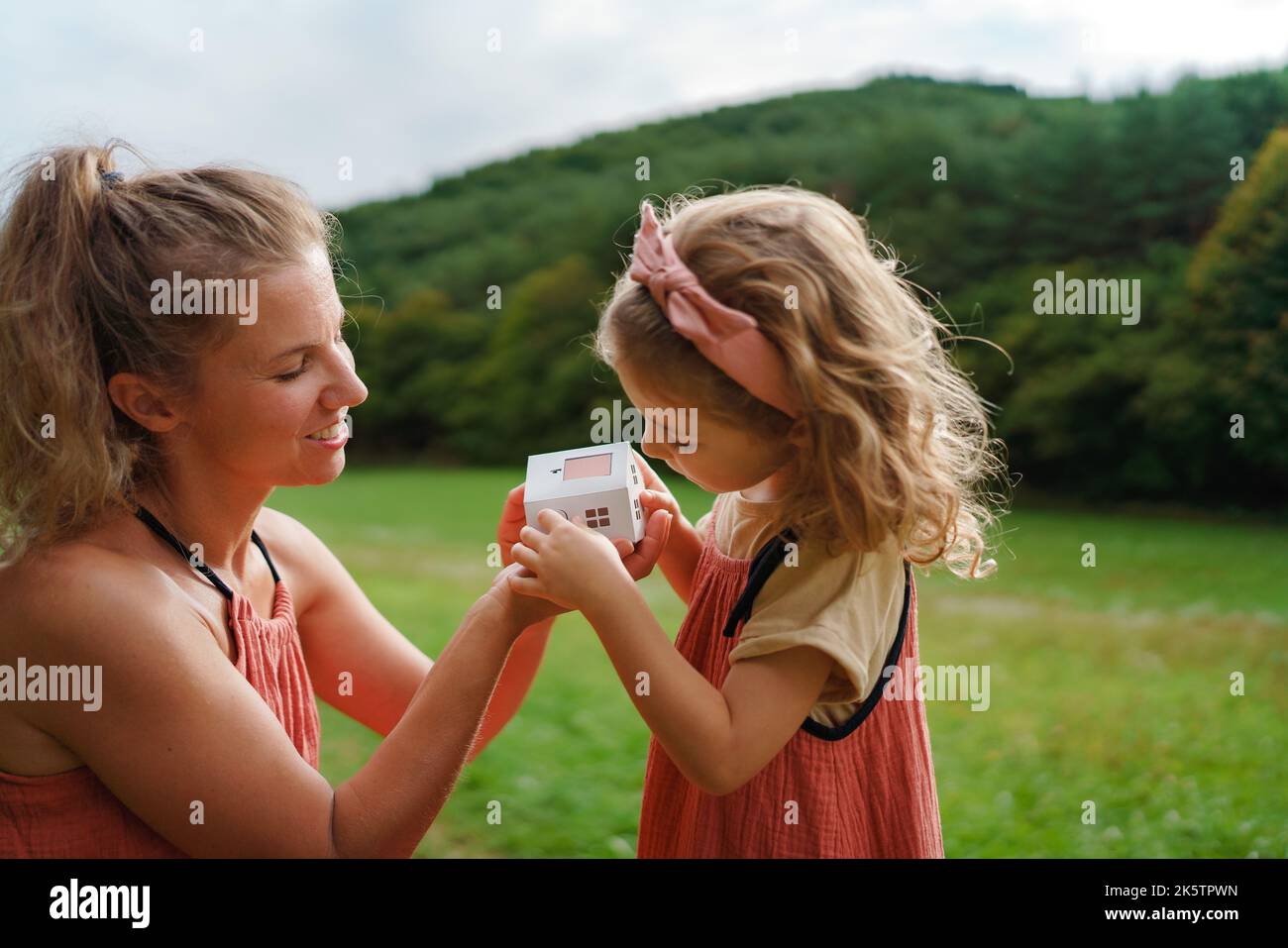 Little girl with her dad holding paper model of house with solar panels ...