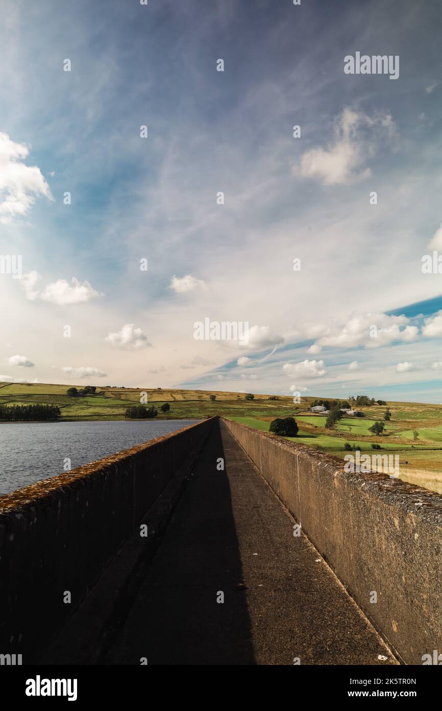 A reservoir walk surrounded by greenery fields and water Stock Photo ...