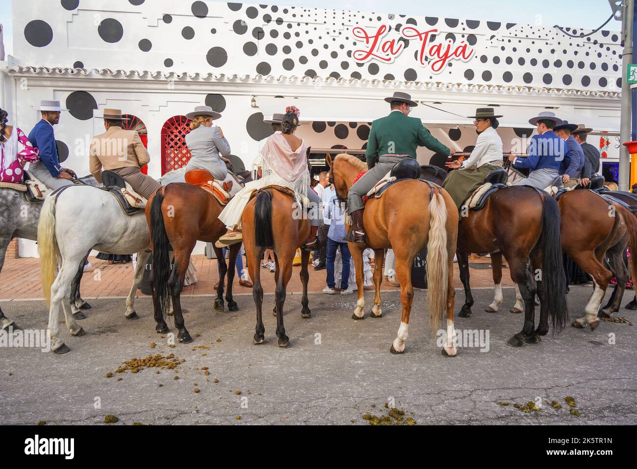Spanish horsemen at a bar, with young woman on back, during annual Fair ...
