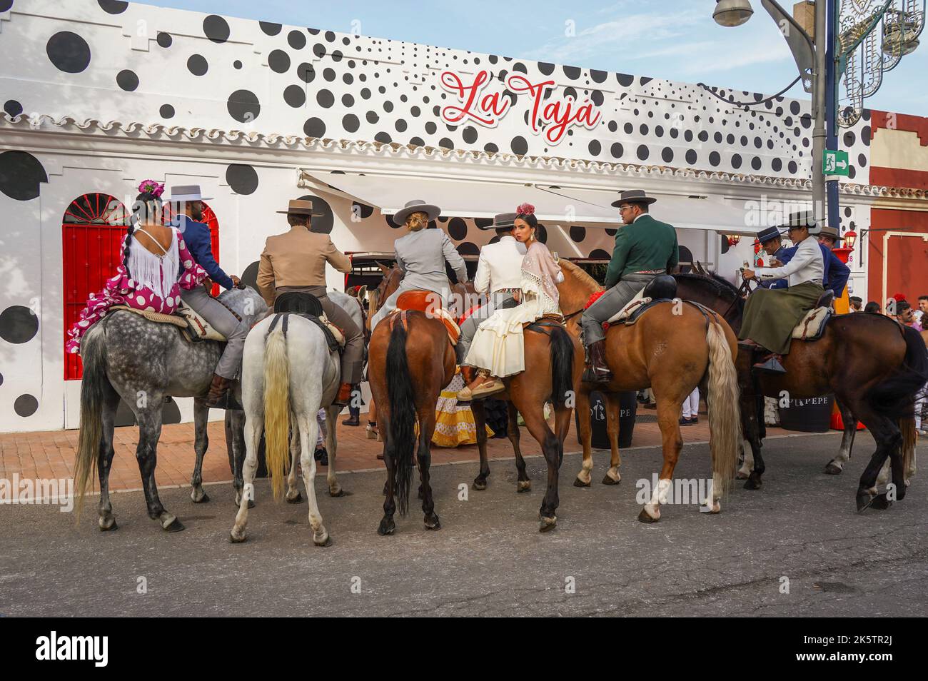 Spanish horsemen at a bar, with young woman on back, during annual Fair ...