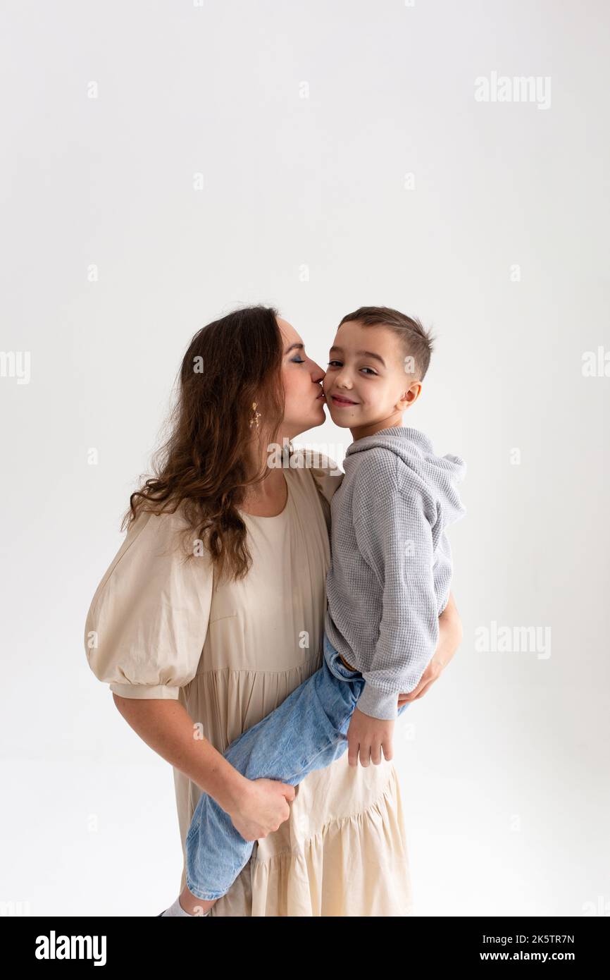 Boy preschooler and mother smile and hug on gray background in photo ...