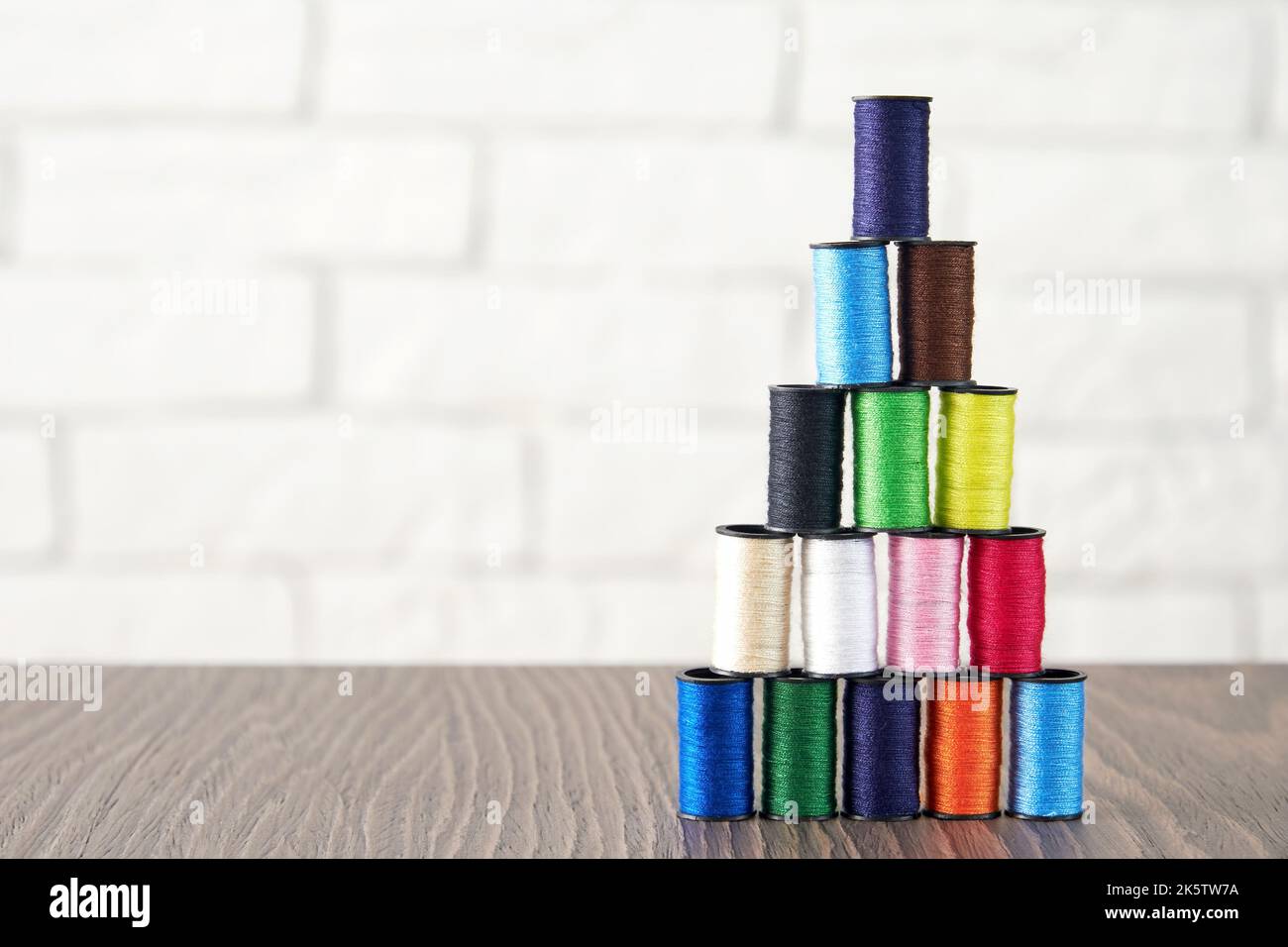 Pyramid of spools of multi-colored sewing threads on the table. Sewing ...