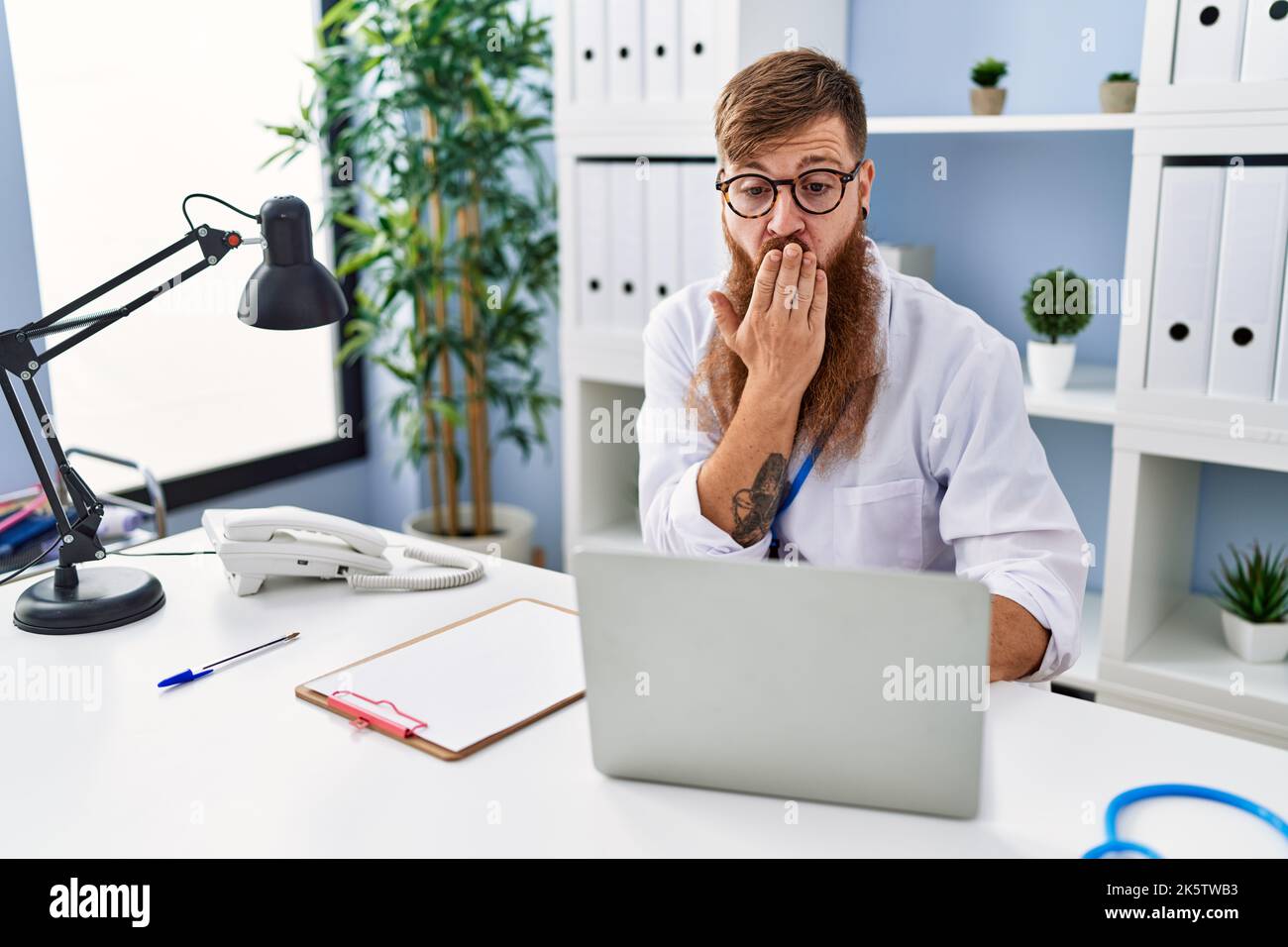 Redhead man with long beard wearing doctor uniform working using ...
