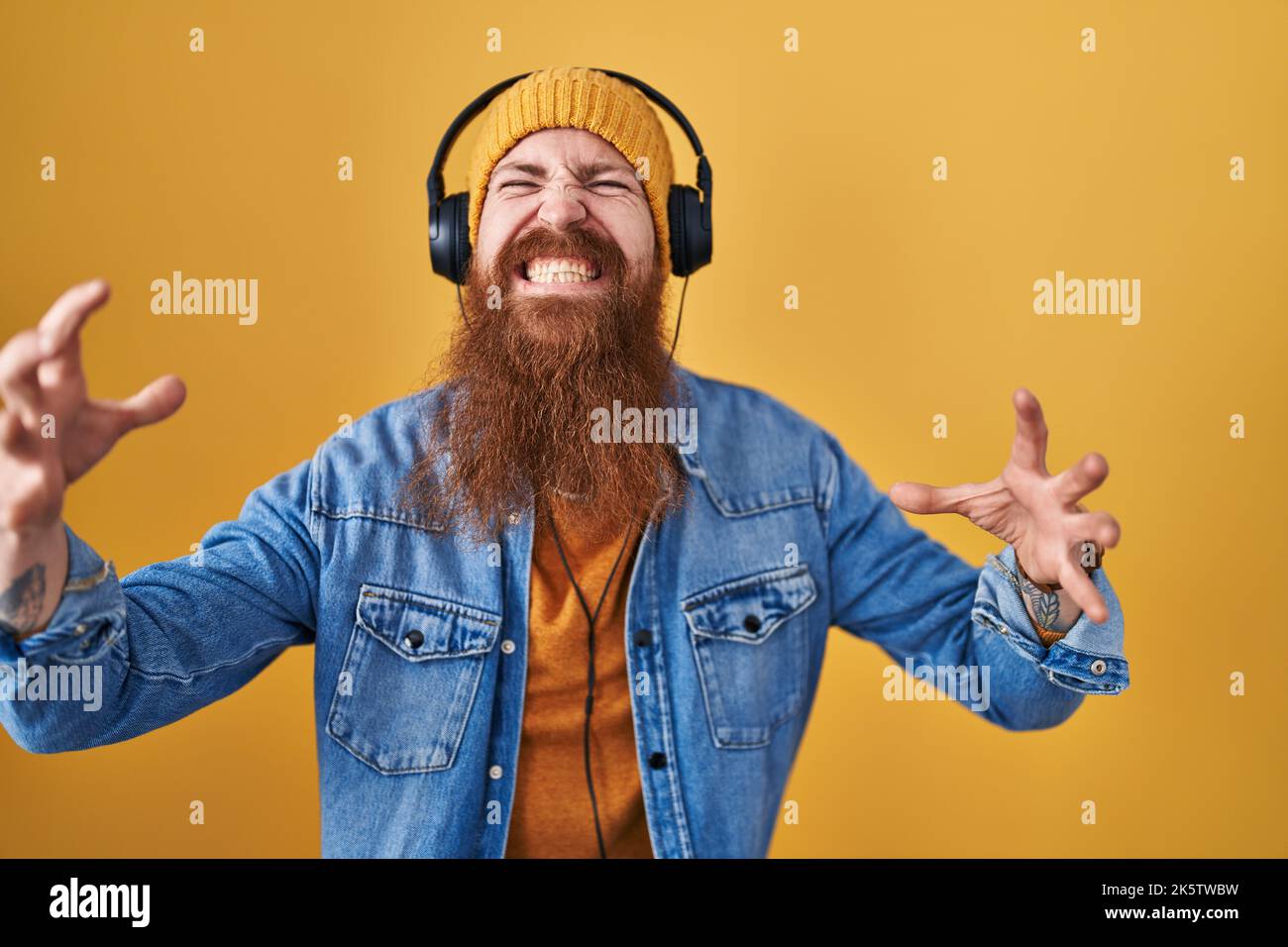Caucasian man with long beard listening to music using headphones ...