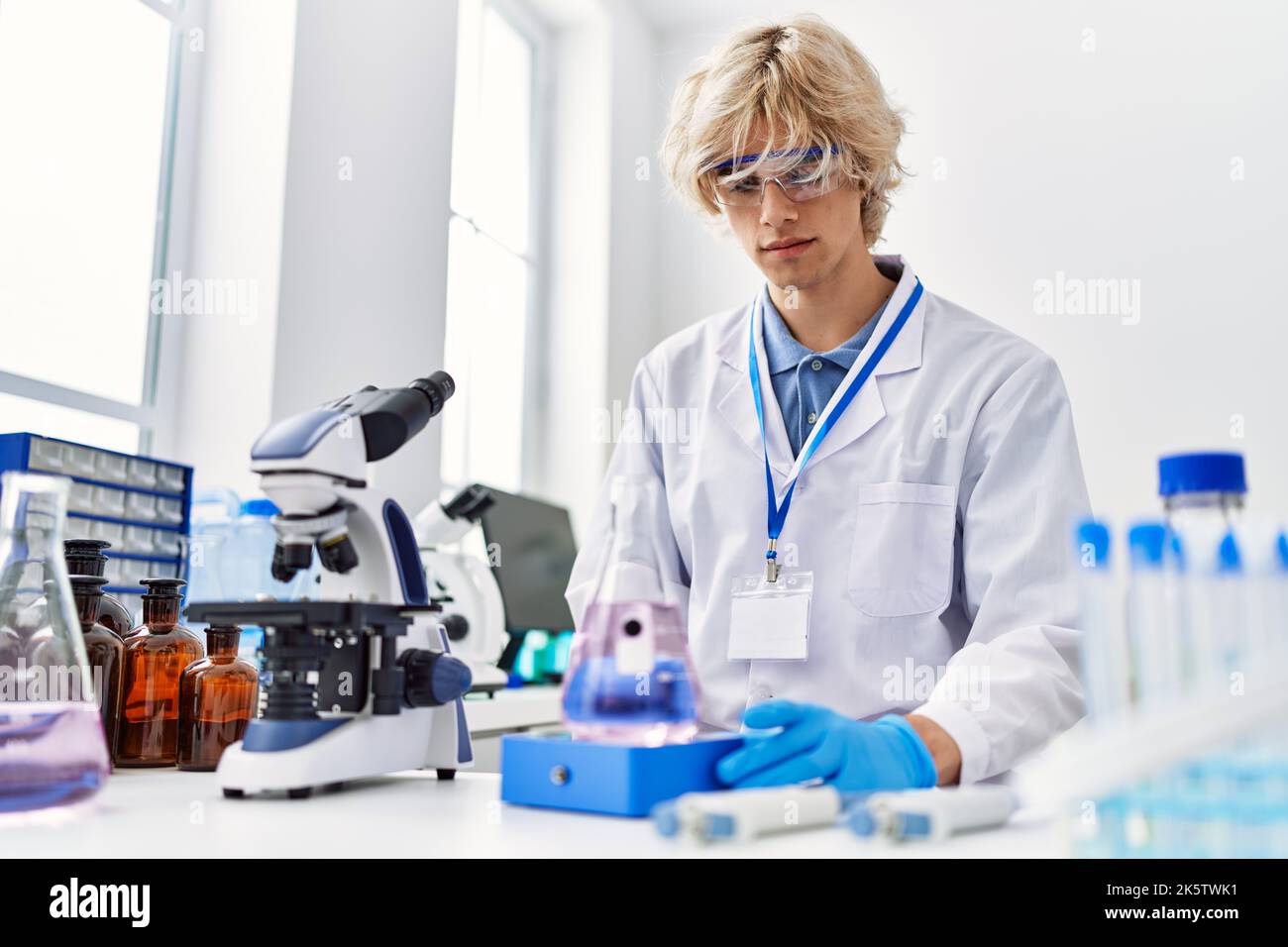 Young blond man scientist weighing test tube at laboratory Stock Photo ...