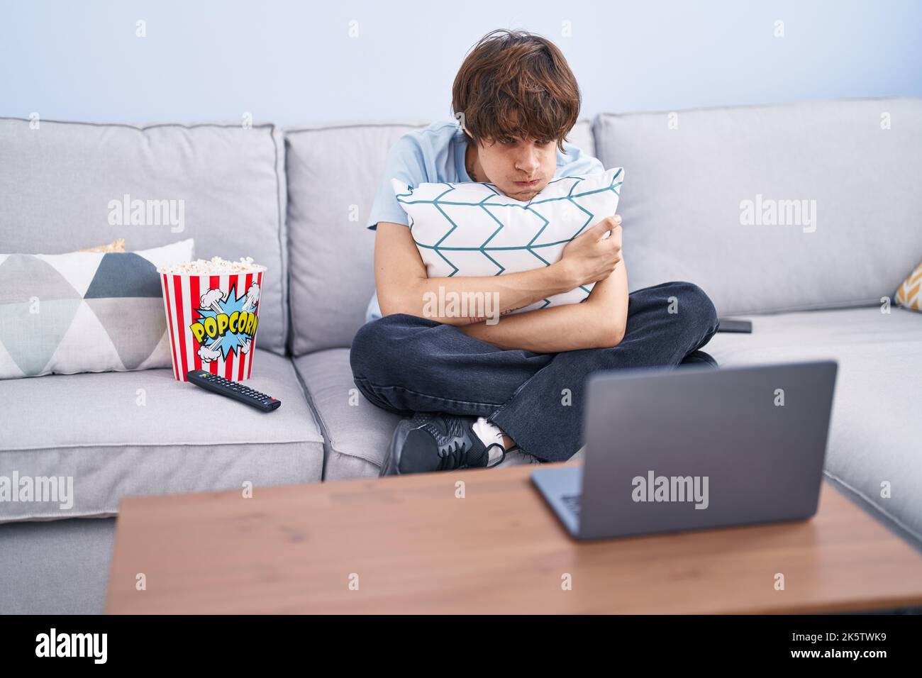 Hispanic young man watching a horror movie in the laptop puffing cheeks ...