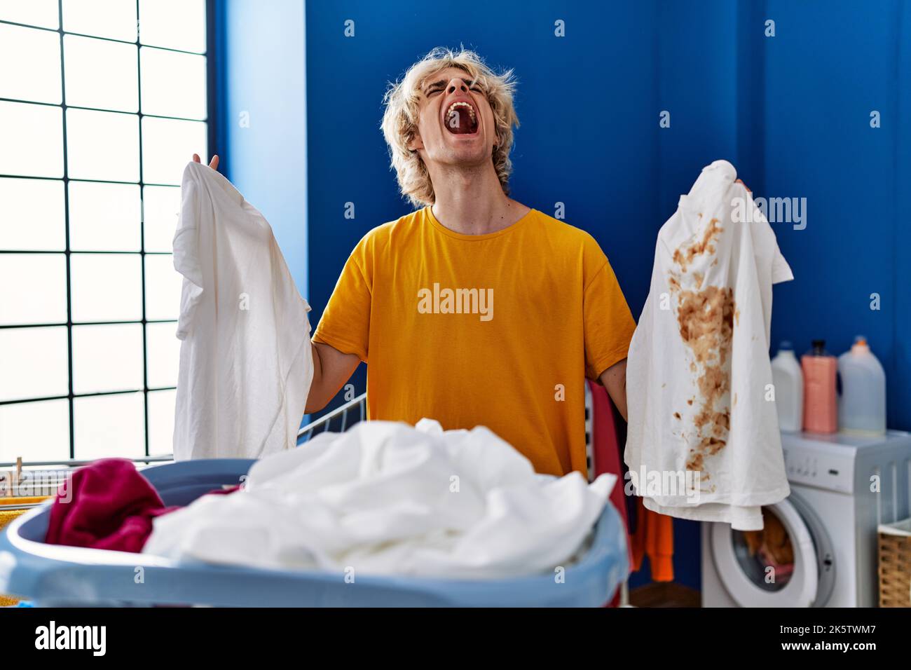 Young man holding clean white t shirt and t shirt with dirty stain ...