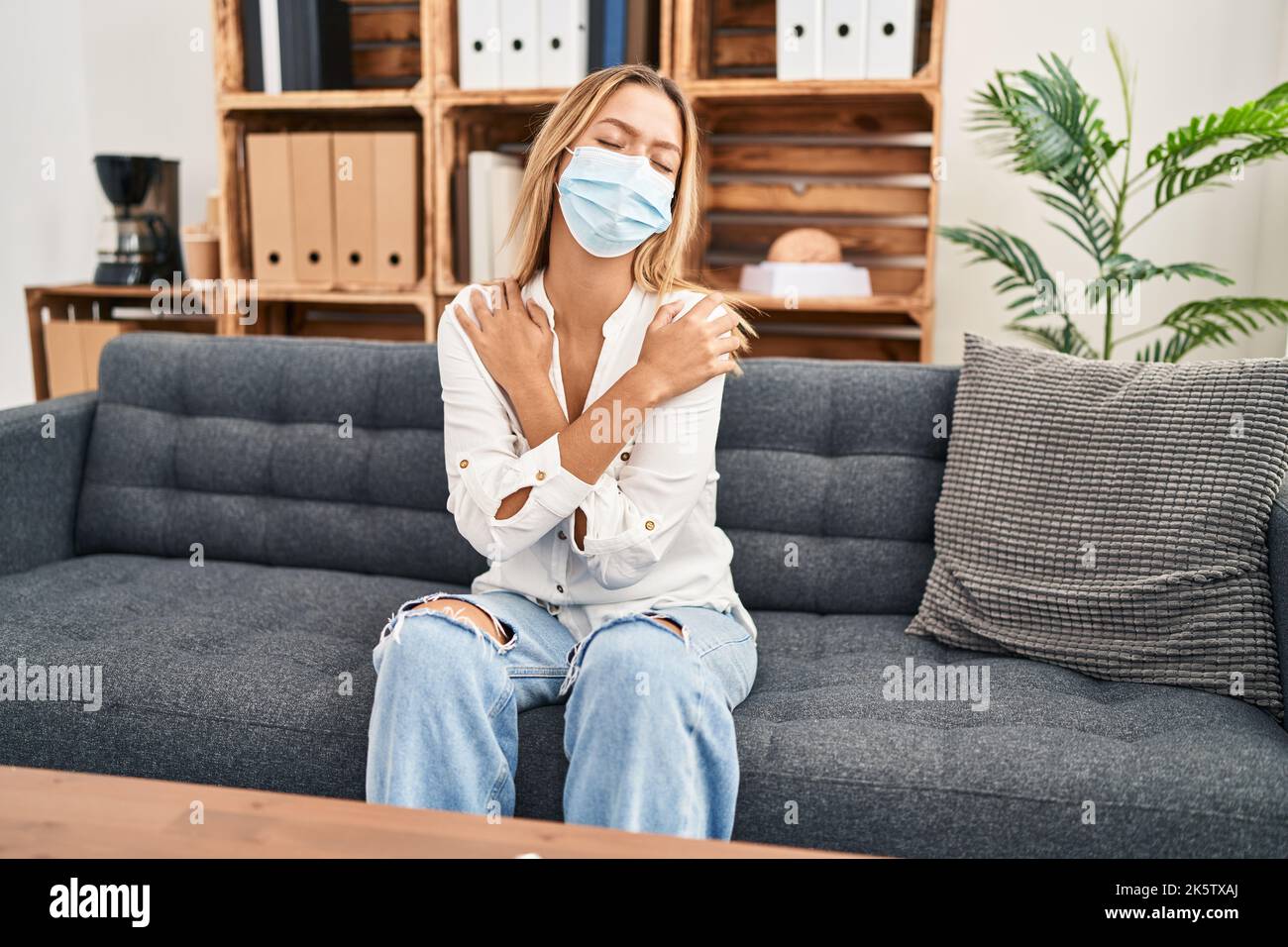 Young blonde woman treating covid fear at therapy hugging oneself happy ...