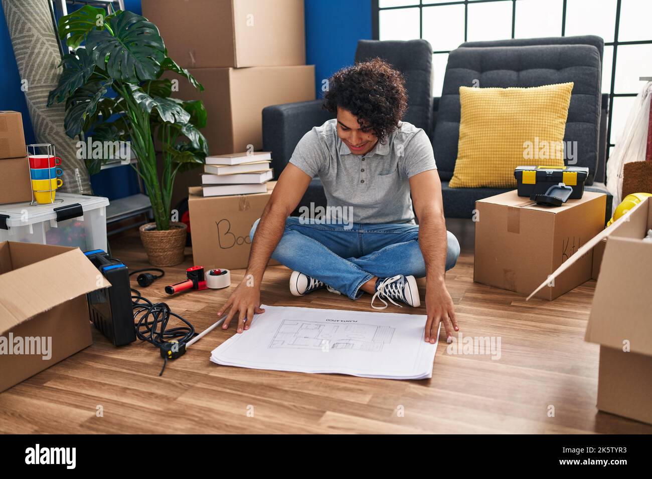 Young hispanic man smiling confident writing on house plan at new home ...