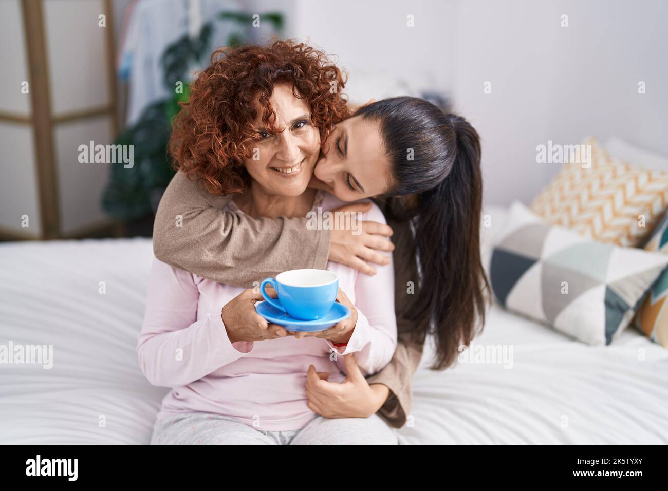 Two Women Mother And Daughter Drinking Coffee Sitting On Bed Stock