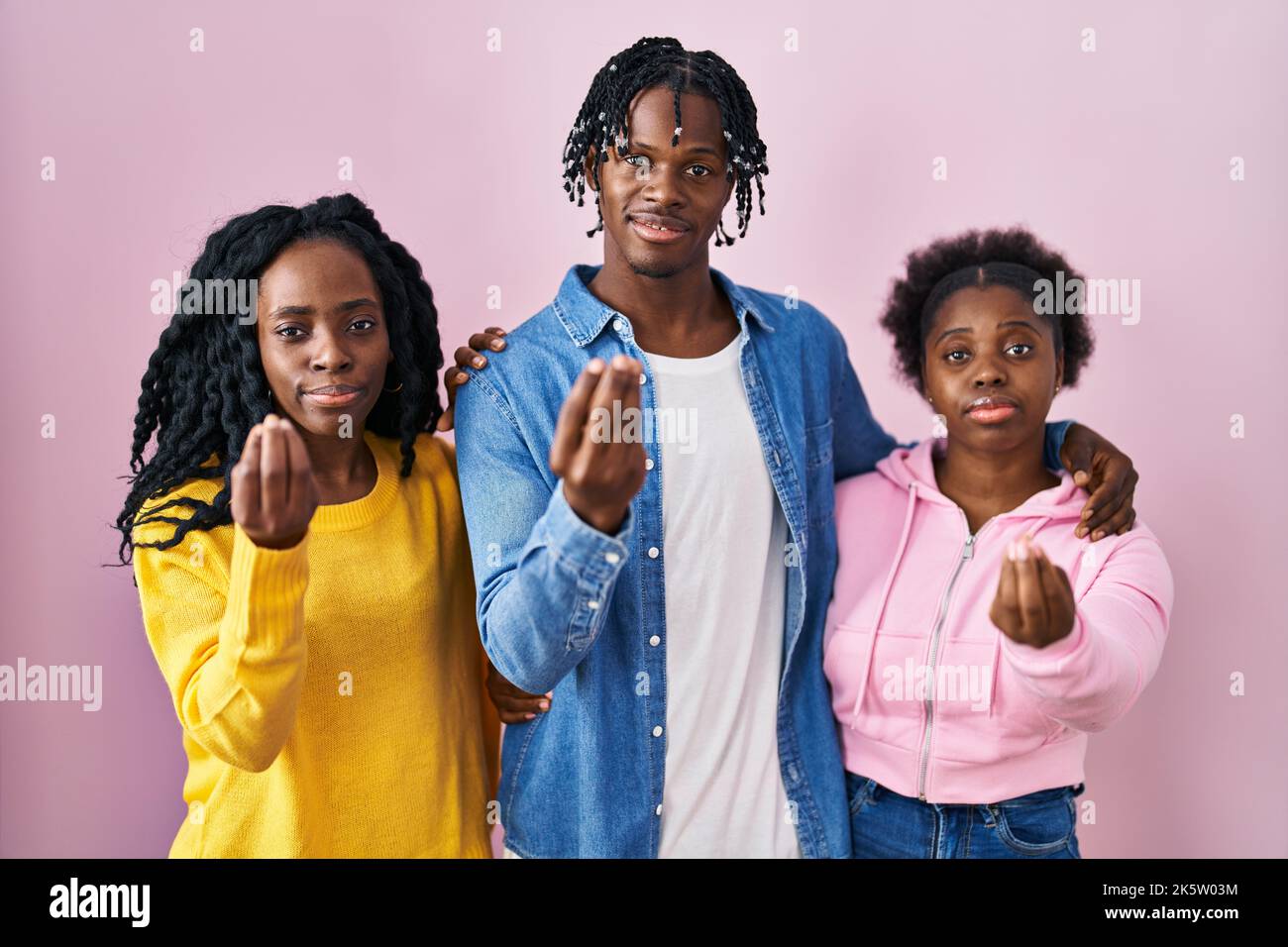 Group of three young black people standing together over pink ...
