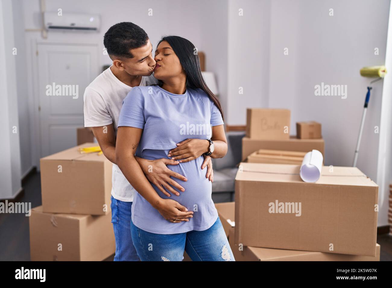 Young latin couple expecting baby hugging each other and kissing at new home Stock Photo - Alamy