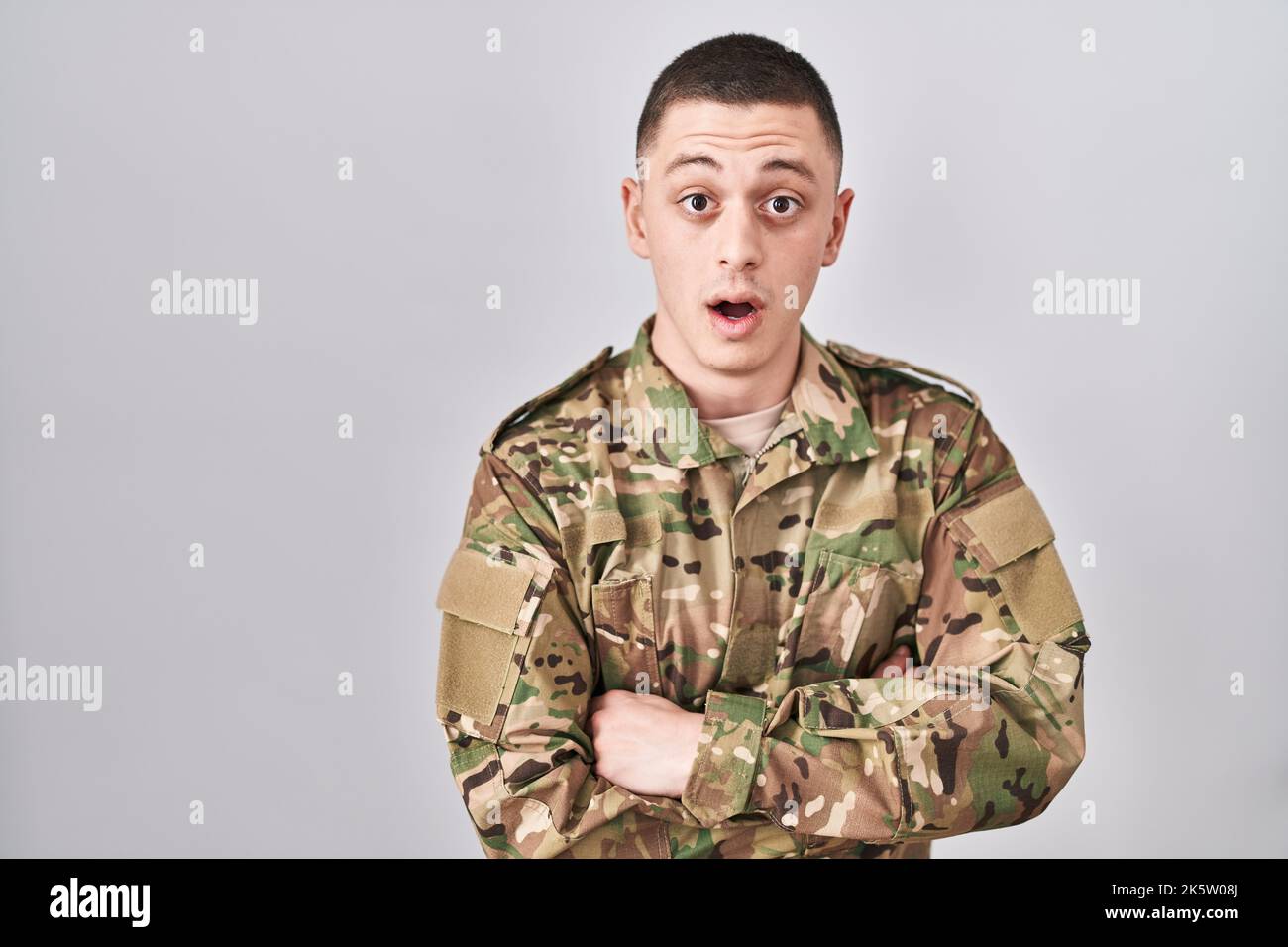 Young man wearing camouflage army uniform afraid and shocked with ...