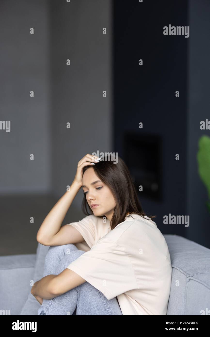 Stressed young woman sitting on sofa Stock Photo - Alamy