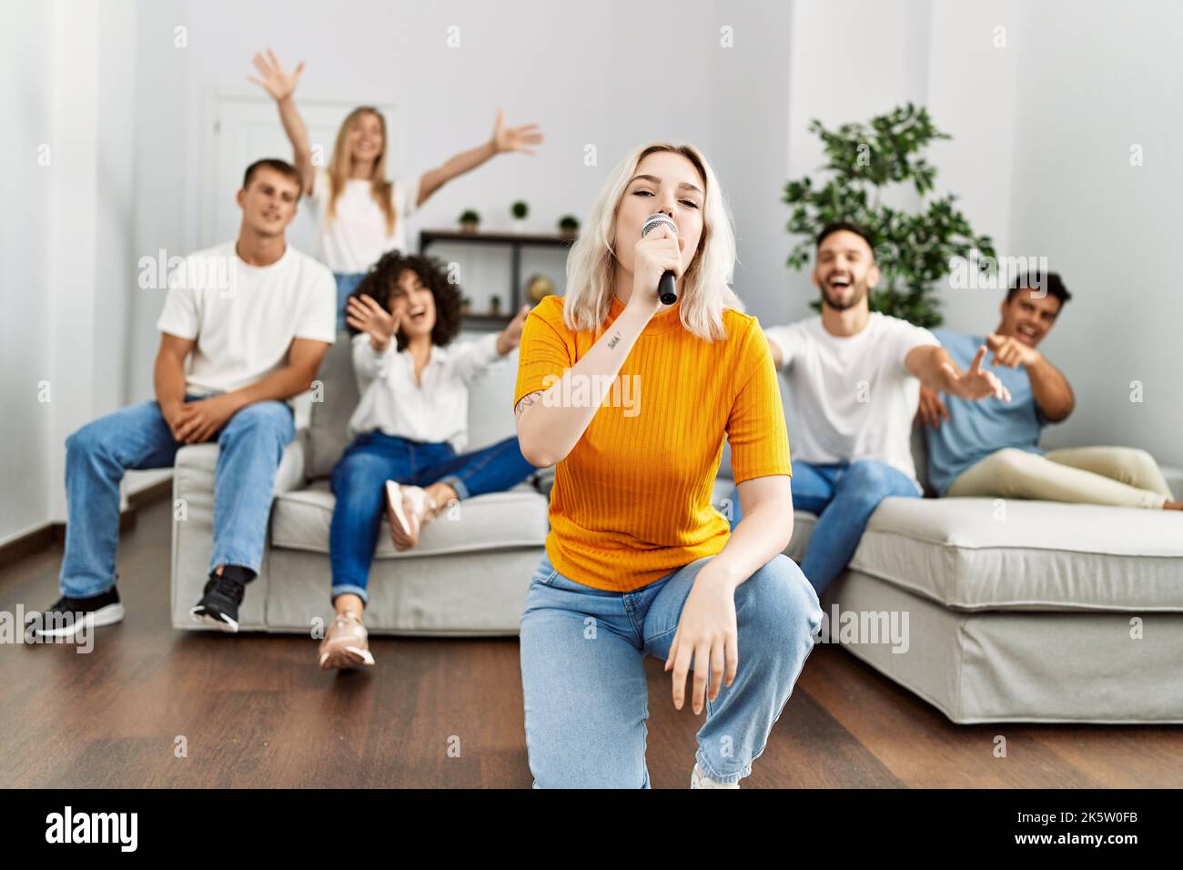 Group of young friends having party singing song using microphone at ...
