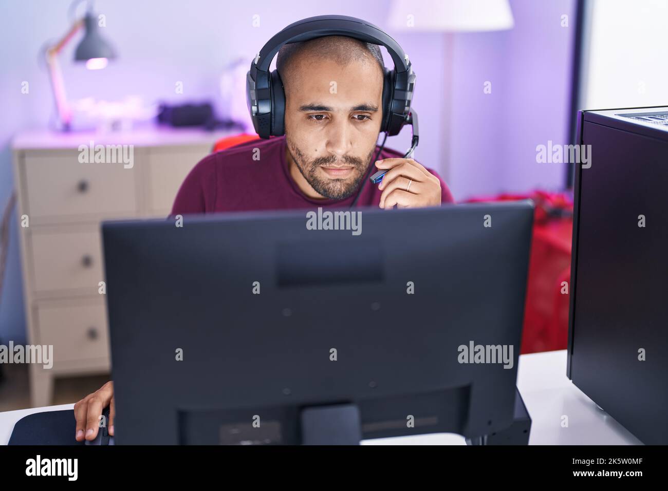 Young latin man streamer playing video game using computer at gaming ...
