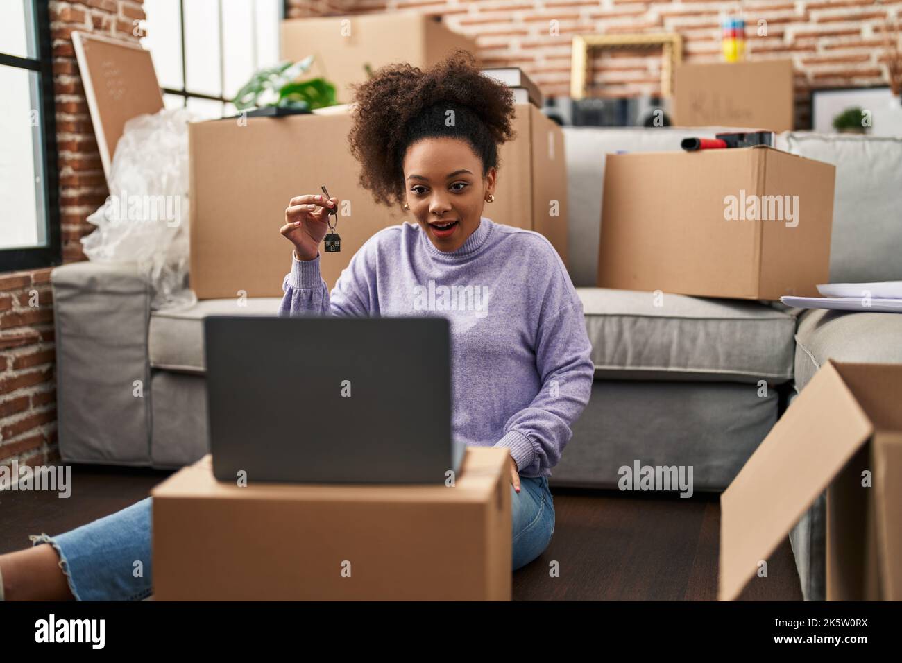 Young african american woman showing keys of new home on video call ...