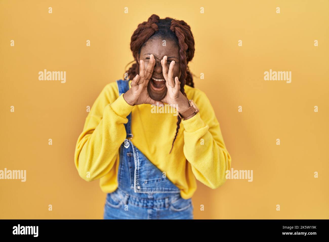 African woman standing over yellow background shouting angry out loud ...