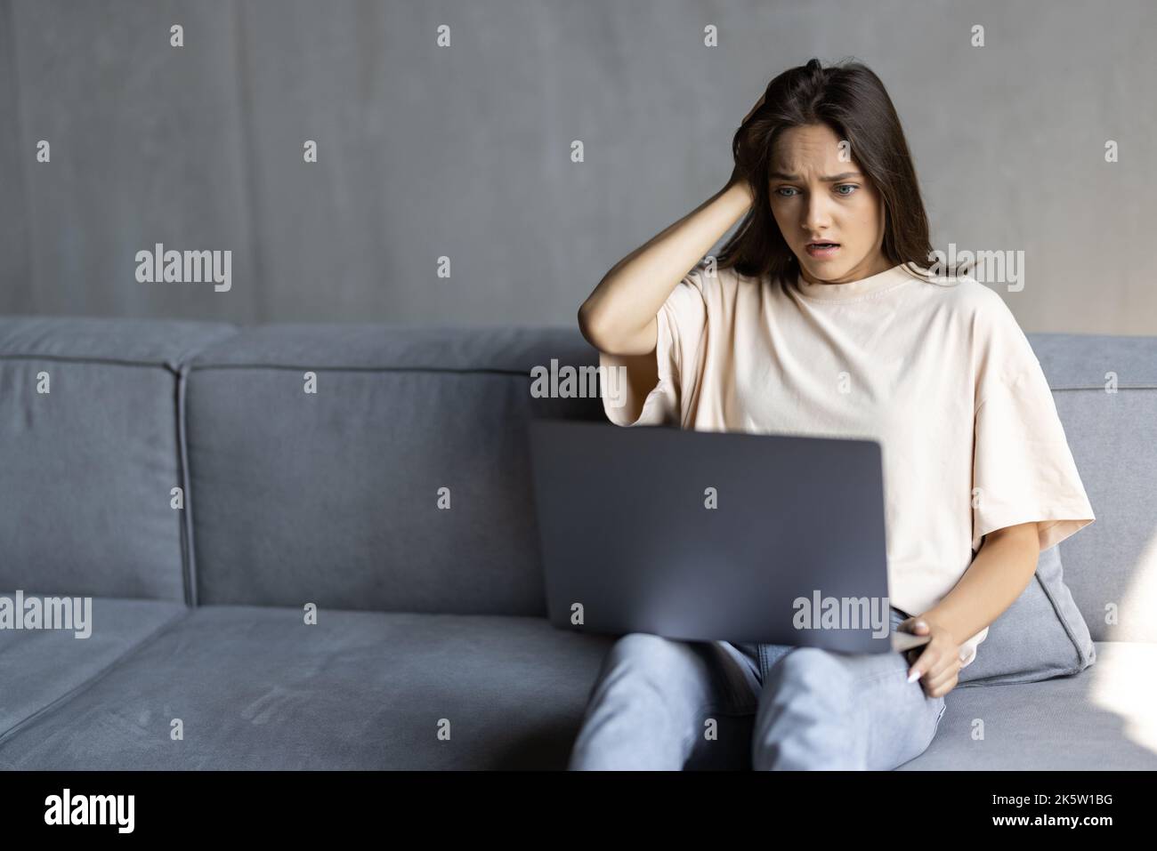 Stressed dissatisfied young woman looking at laptop screen, touching ...