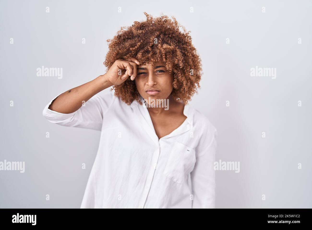 Young hispanic woman with curly hair standing over white background ...