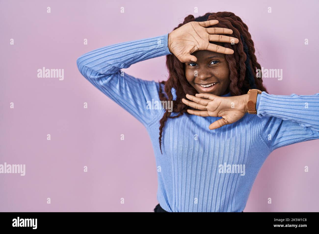 African woman standing over pink background smiling cheerful playing ...
