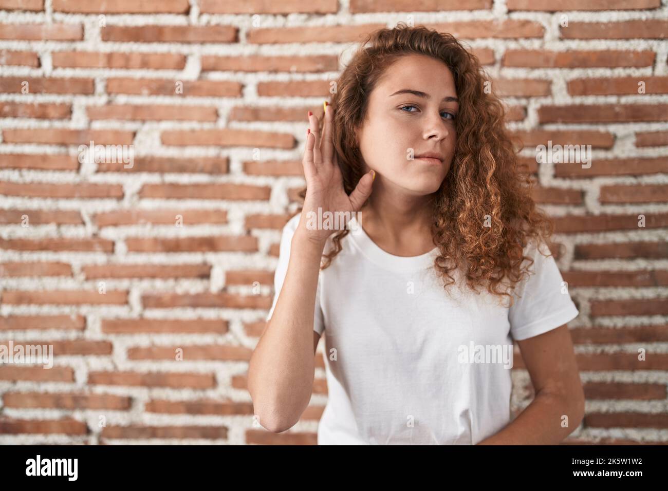 Young caucasian woman standing over bricks wall background smiling with ...