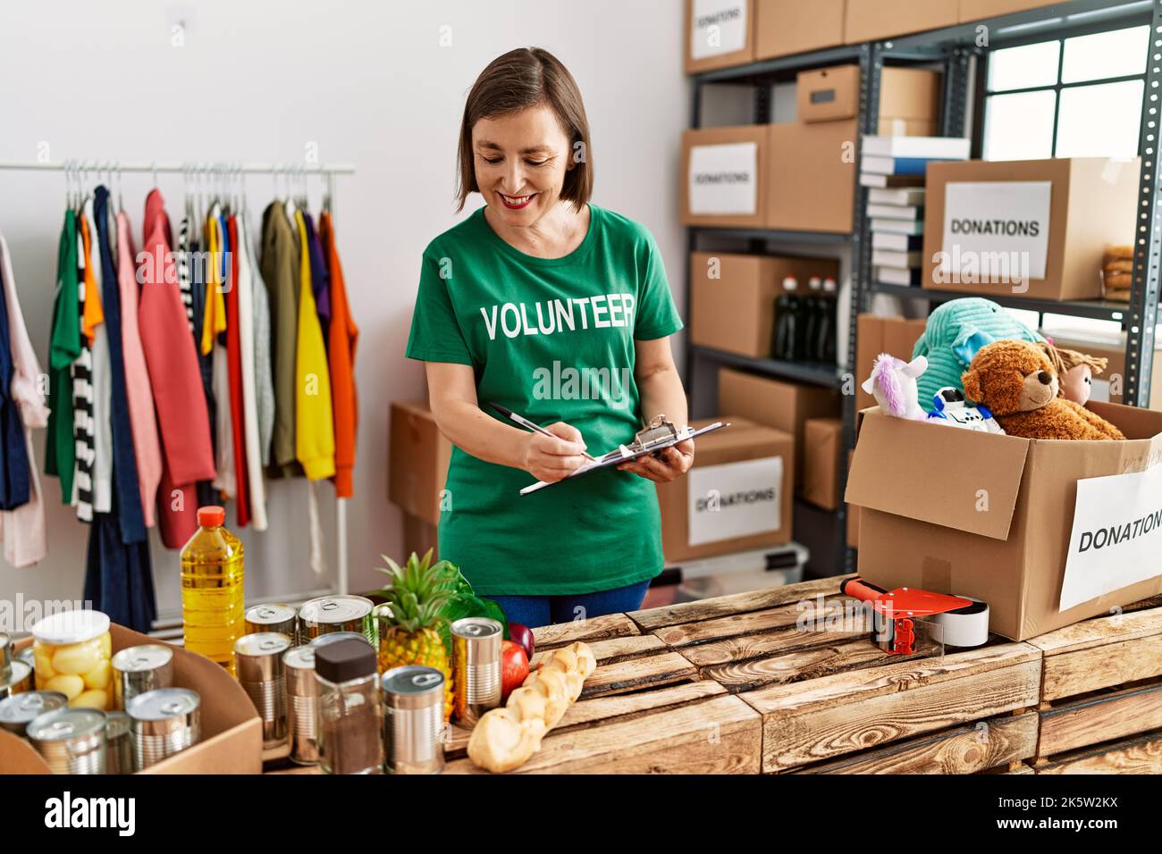 Middle age hispanic woman checking donations on checklist at donations ...