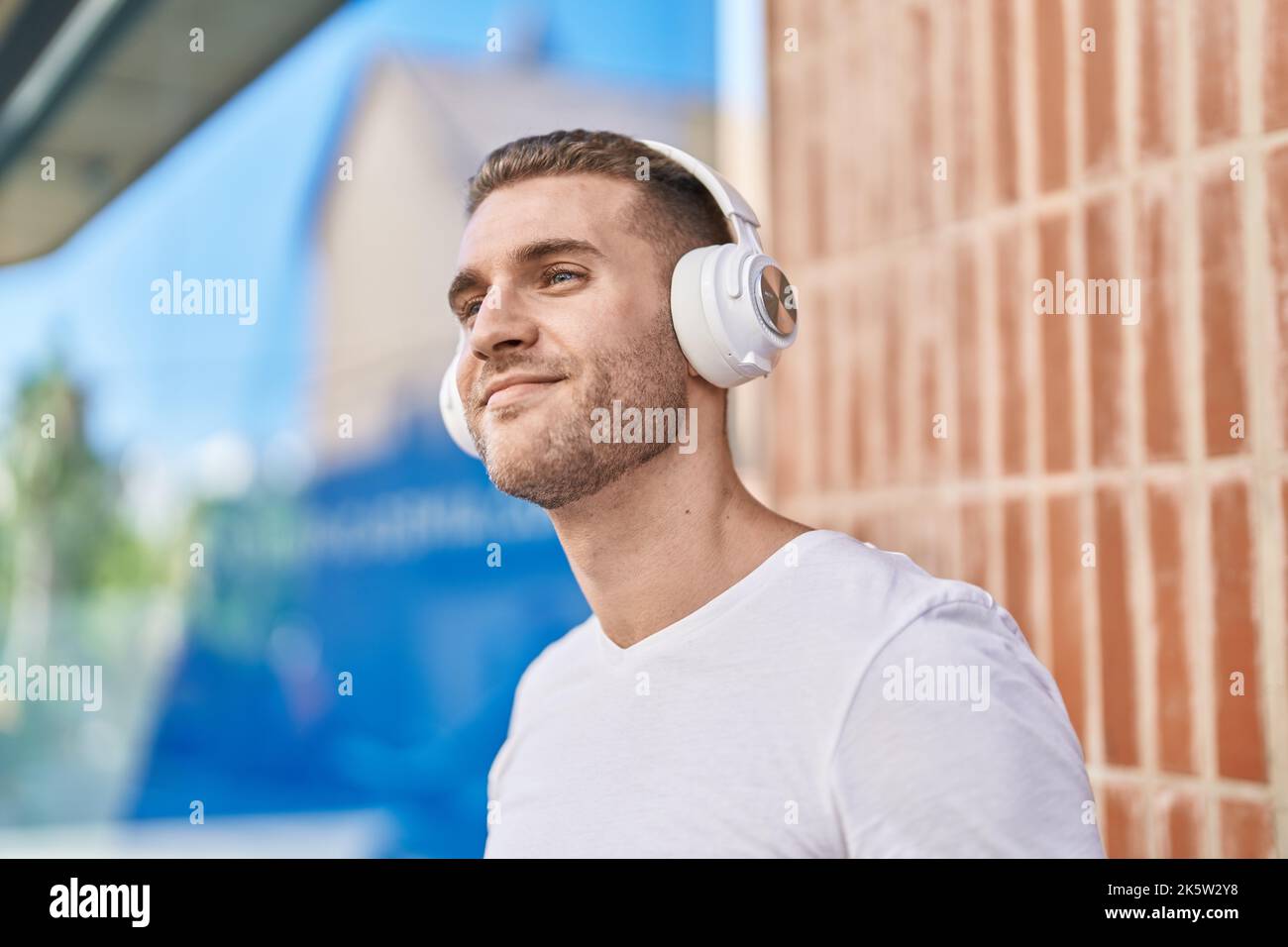Young caucasian man listening to music standing at street Stock Photo ...