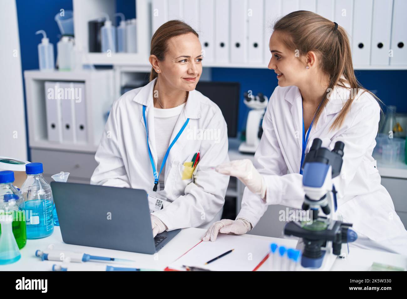 Two women scientists using laptop holding sample at laboratory Stock ...