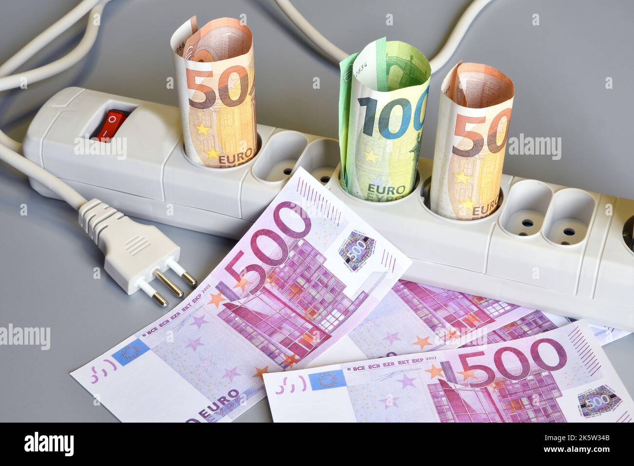 Euro banknotes rolled up and inserted into the electrical sockets of an ...