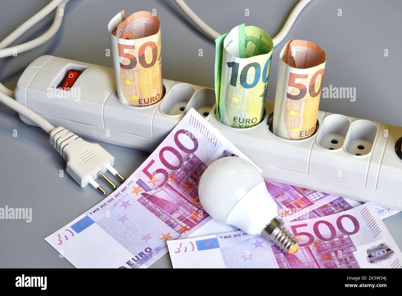 Euro banknotes rolled up and inserted into the electrical sockets of an ...