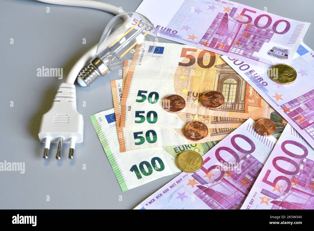 Electric plug, euro money banknotes and cents with light bulb over grey ...