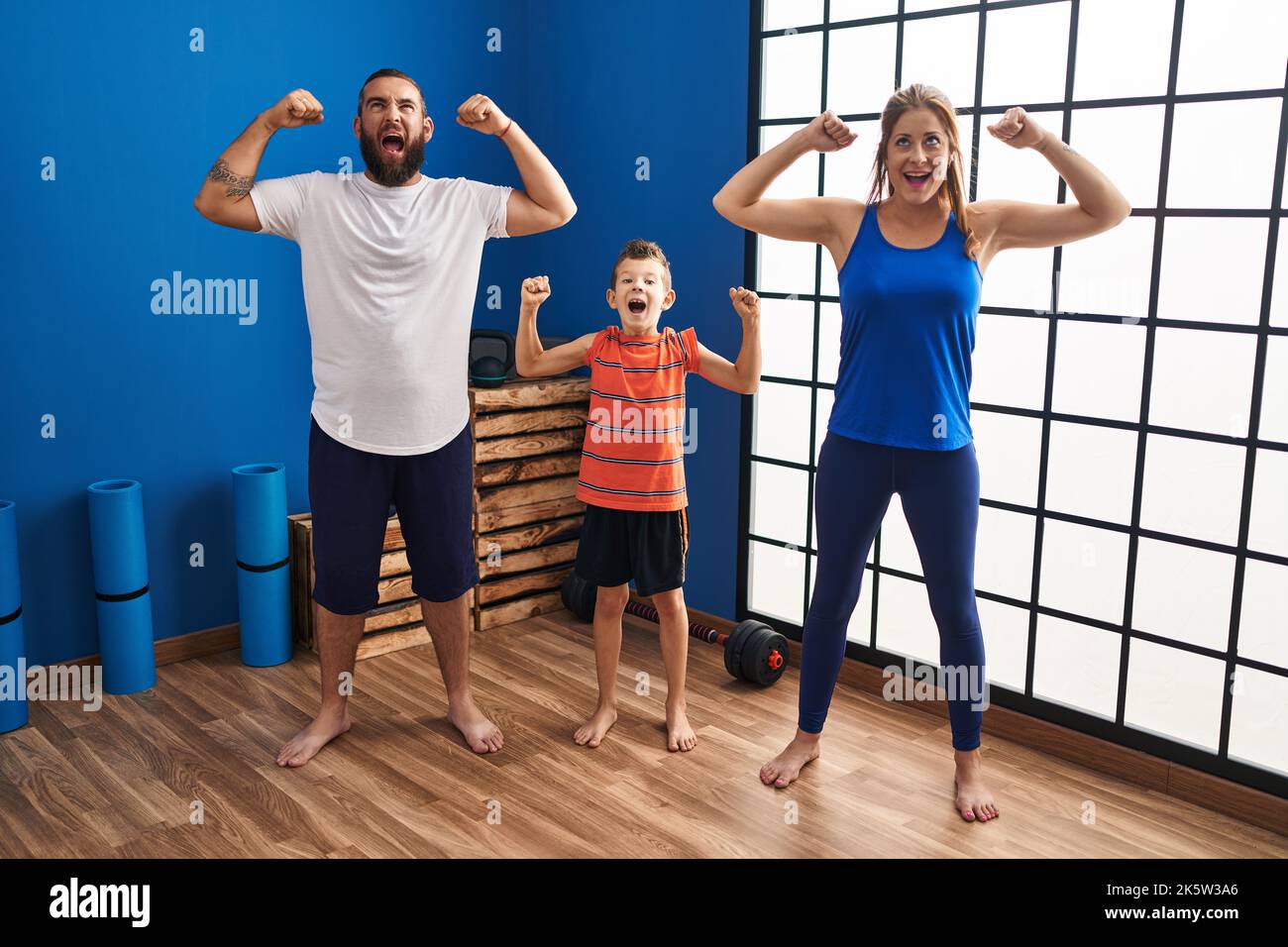 Family of three wearing sportswear at the gym angry and mad screaming ...