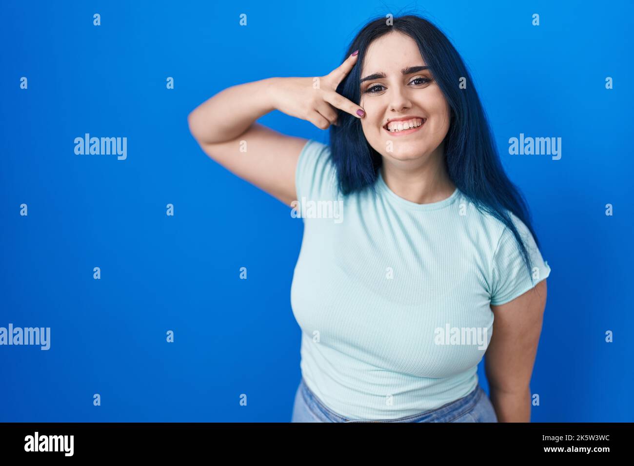 Young Modern Girl With Blue Hair Standing Over Blue Background Doing 1886