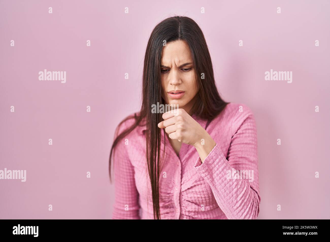Young hispanic woman standing over pink background feeling unwell and ...