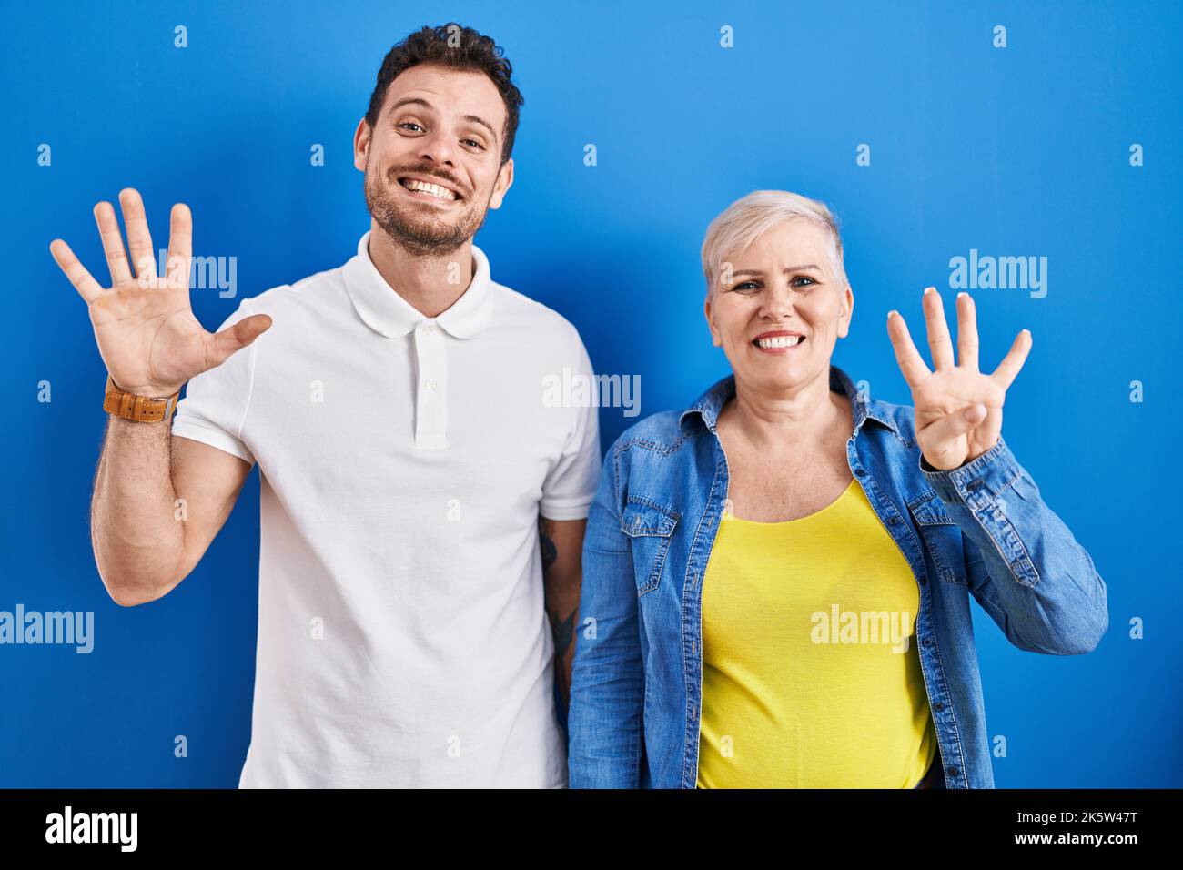 Young brazilian mother and son standing over blue background showing ...